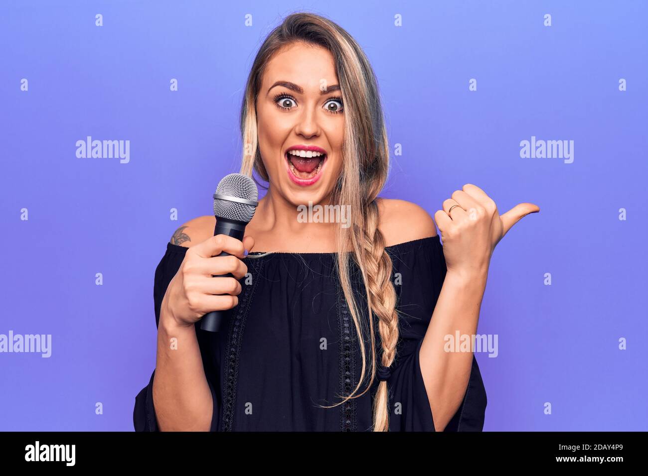 Young beautiful blonde singer woman singing using microphone over ...