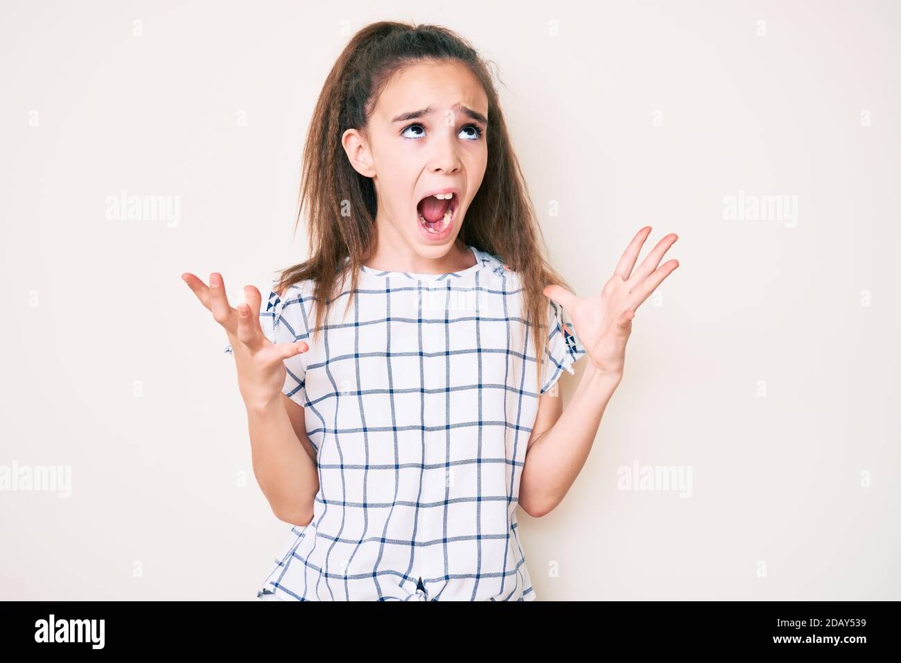 Cute hispanic child girl wearing casual clothes crazy and mad shouting ...