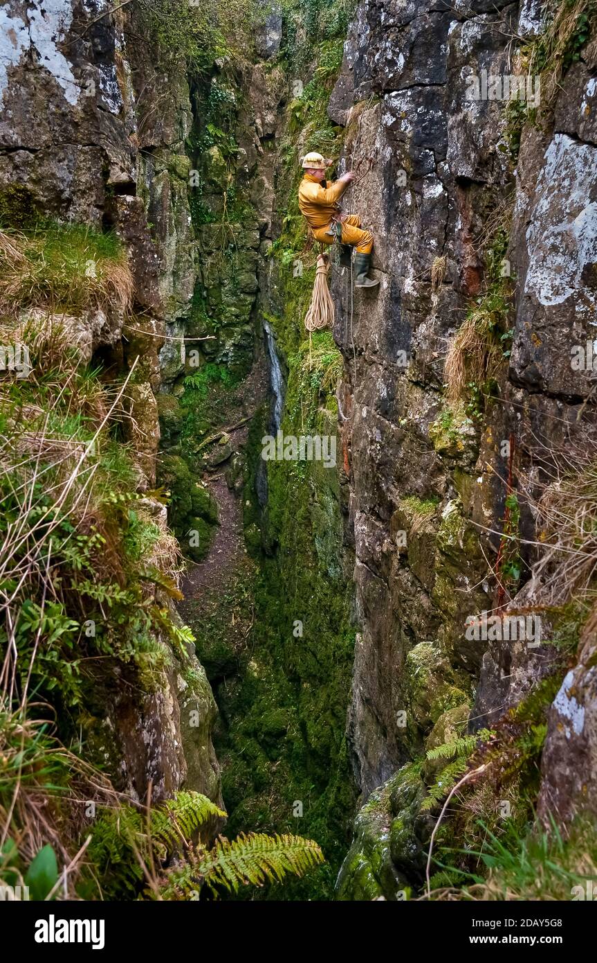A caver rigging ropes to descend the gaping chasm of Eldon Hole, an ...
