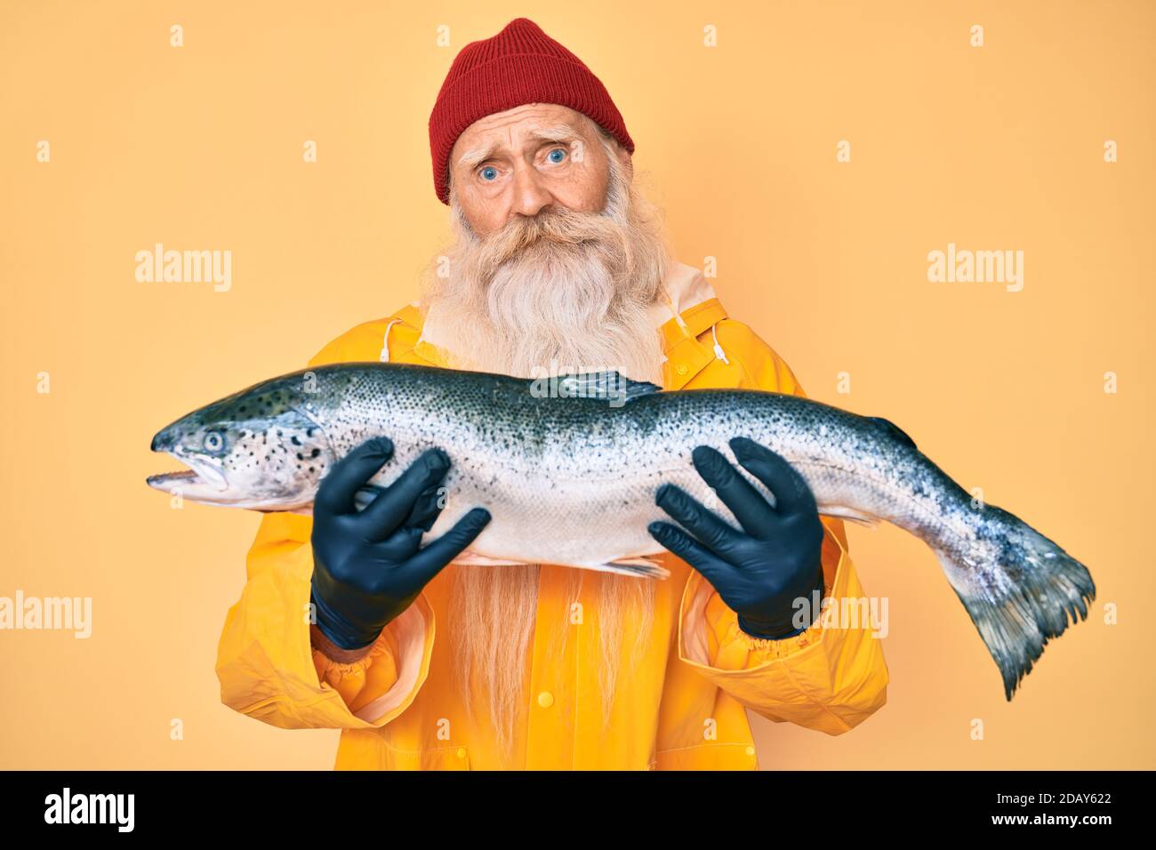 Old senior man with grey hair and long beard wearing raincoat holding ...