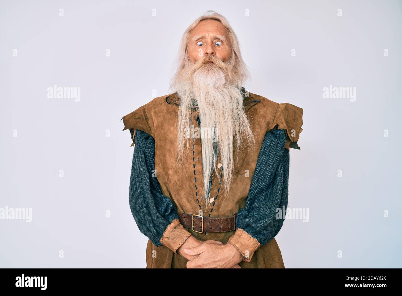 Old senior man with grey hair and long beard wearing viking traditional ...