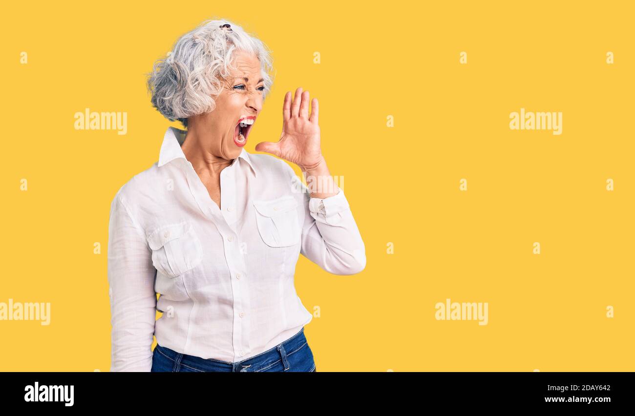 Senior grey-haired woman wearing casual clothes shouting and screaming ...