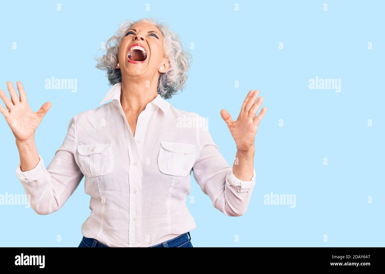 Senior grey-haired woman wearing casual clothes crazy and mad shouting ...
