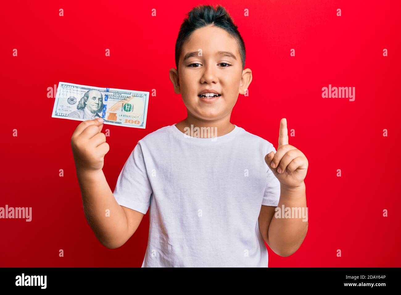 Little boy hispanic kid holding 100 dollars banknote smiling with an ...