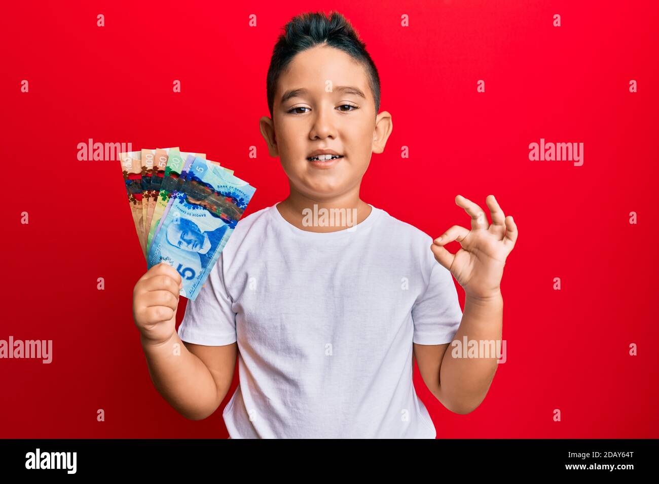Little boy hispanic kid holding canadian dollars doing ok sign with ...