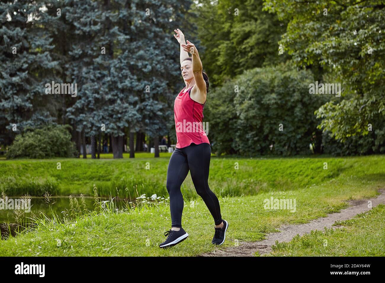 Young healthy woman makes exercises in public park near pond Stock ...