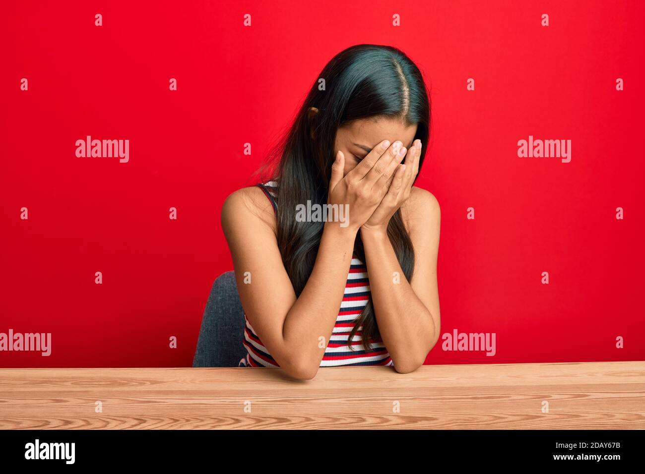 Beautiful hispanic woman wearing casual clothes sitting on the table ...