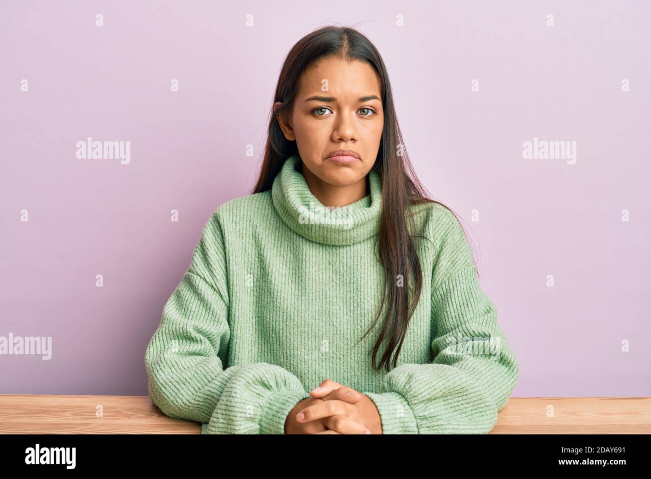 Beautiful hispanic woman wearing casual clothes sitting on the table ...