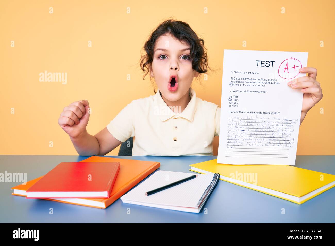Cute hispanic child showing a passed exam sitting on the desk scared ...