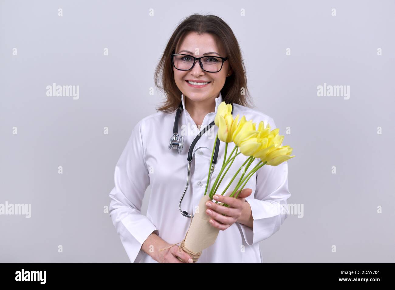 Portrait of female doctor with stethoscope holding bouquet of flowers ...