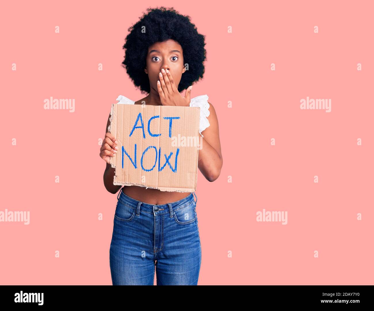 Young african american woman holding act now banner covering mouth with ...