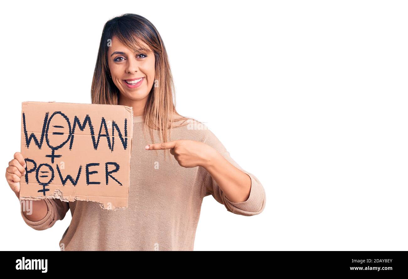 Young beautiful woman holding woman power banner smiling happy pointing ...