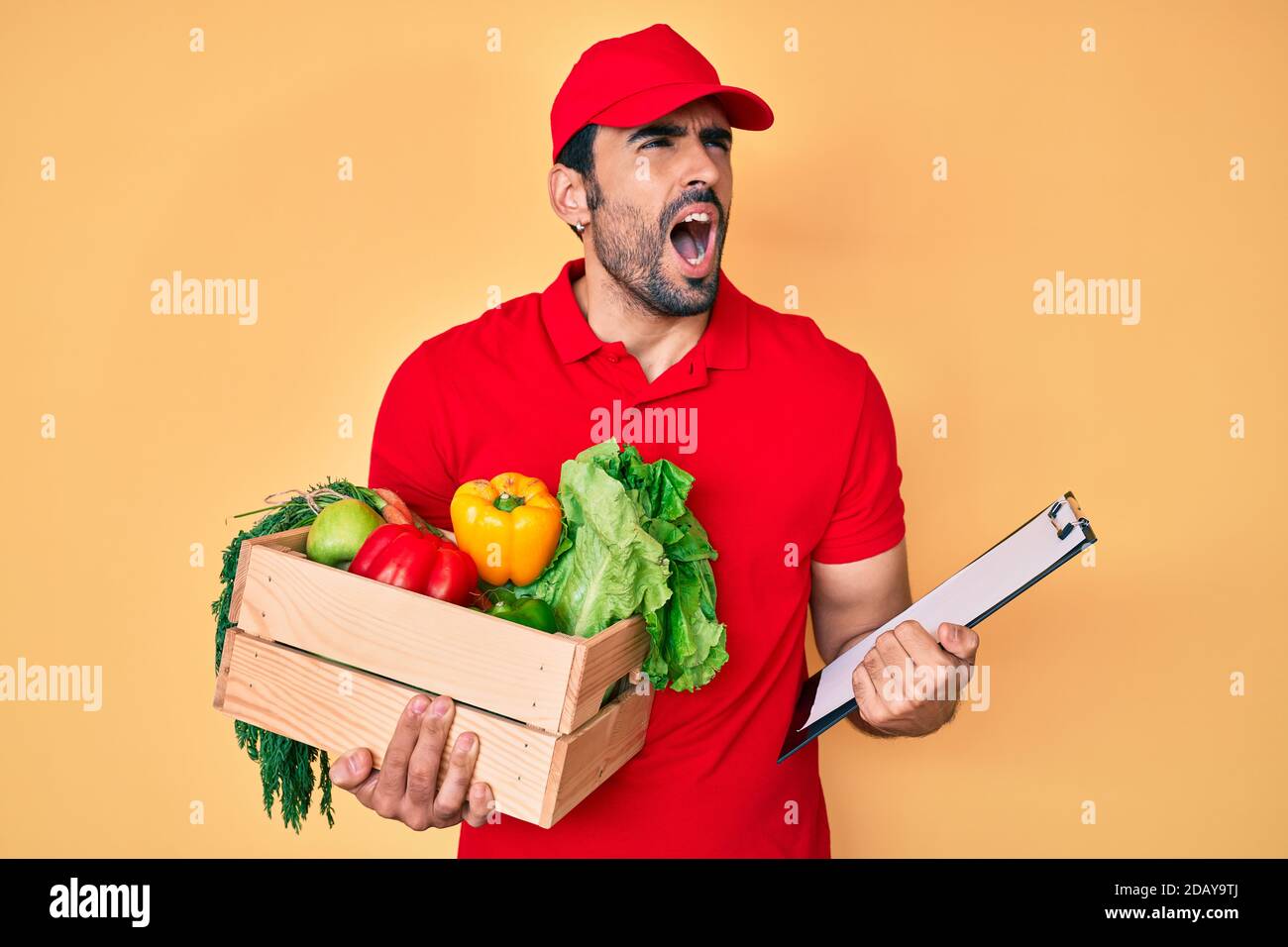Handsome hispanic man with beard wearing uniform holding delivery food ...