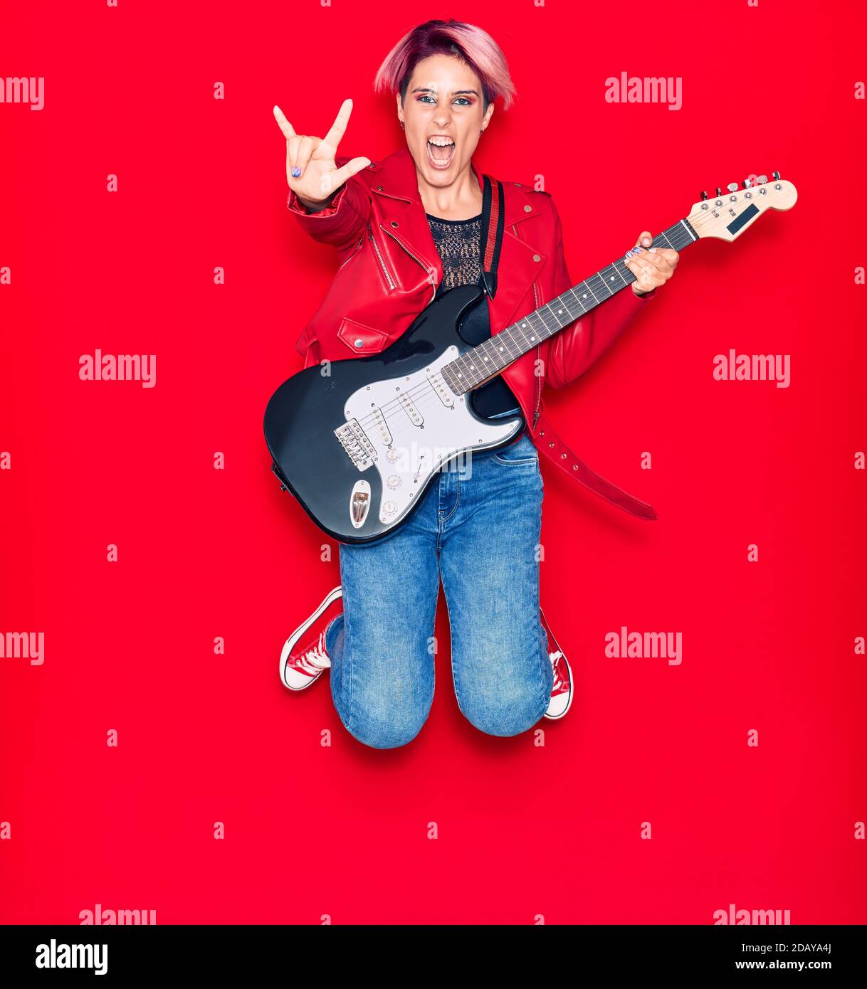 Young beautiful guitarist woman with pink short hair playing electric ...