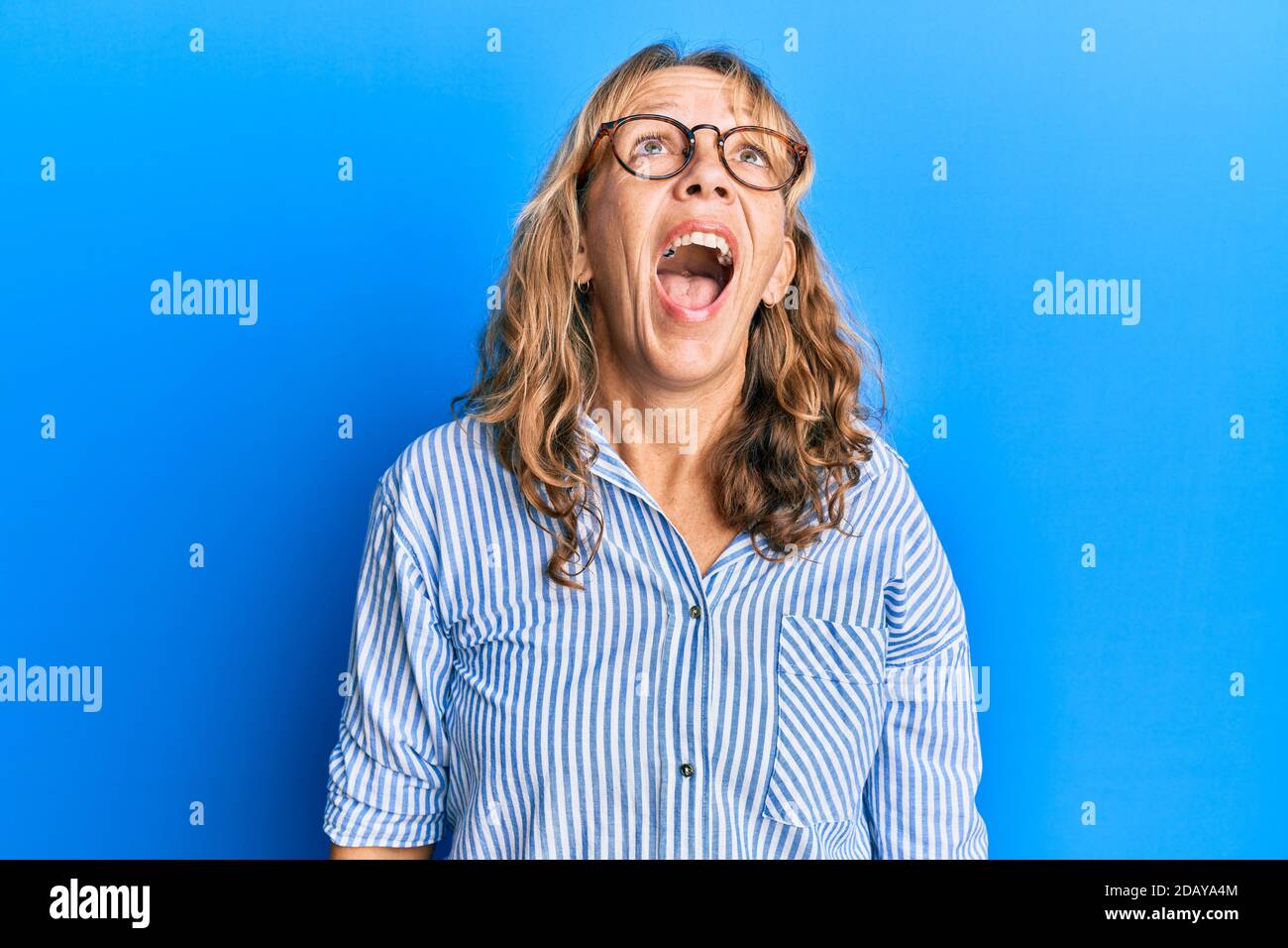 Middle age blonde woman wearing casual clothes and glasses angry and ...