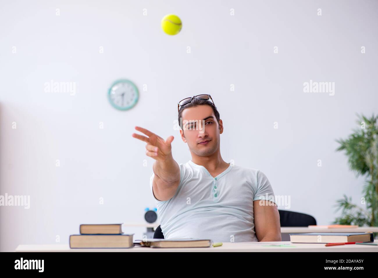 Male student throwing tennis ball during exam preparation in the ...