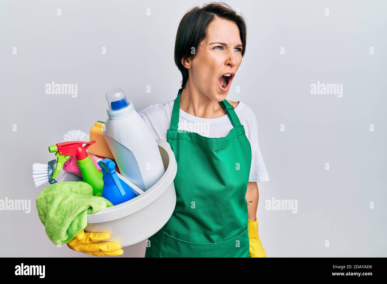 Young brunette woman with short hair wearing apron holding cleaning ...