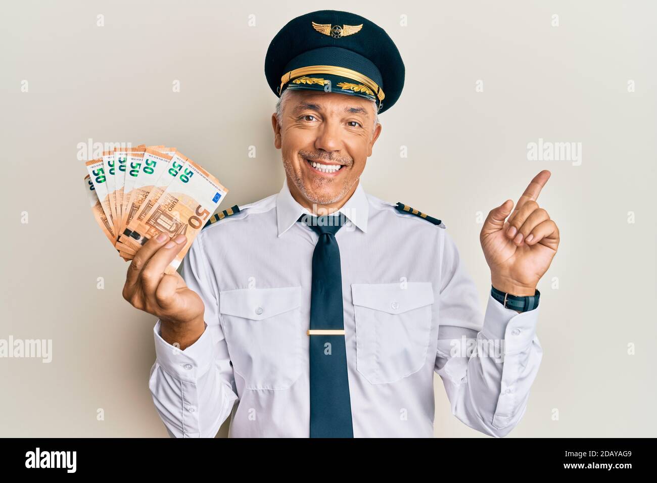 Handsome middle age mature man wearing airplane pilot uniform holding ...