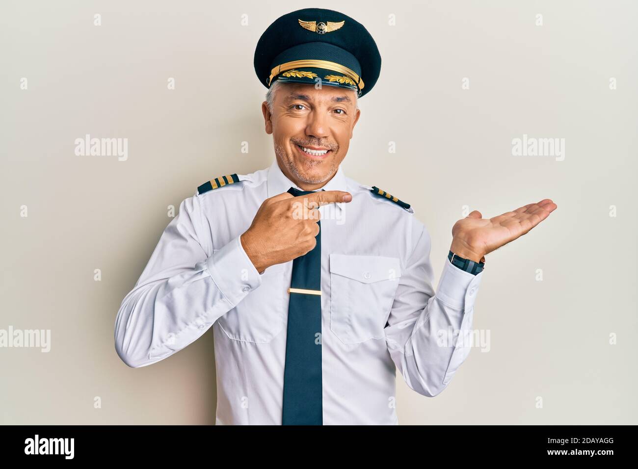 Handsome middle age mature man wearing airplane pilot uniform amazed ...