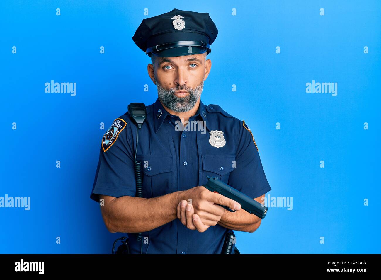Middle age handsome man wearing police uniform holding gun depressed ...