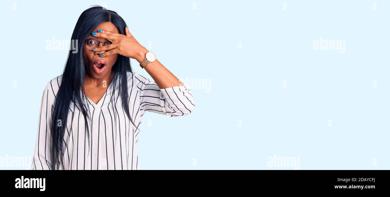 Young african american woman wearing casual clothes and glasses peeking ...