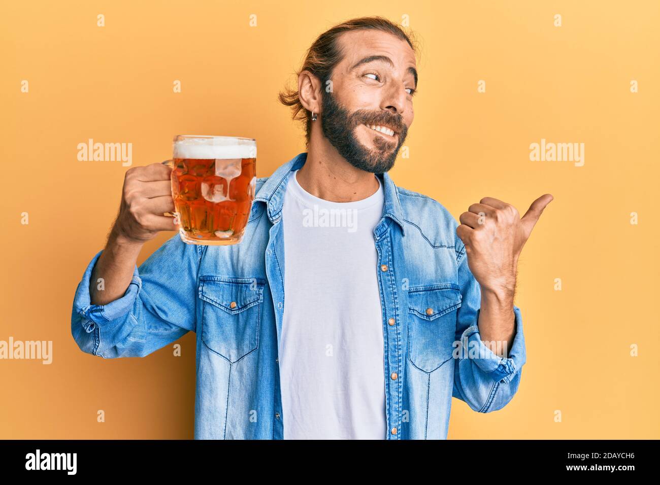 Attractive man with long hair and beard drinking a pint of beer ...
