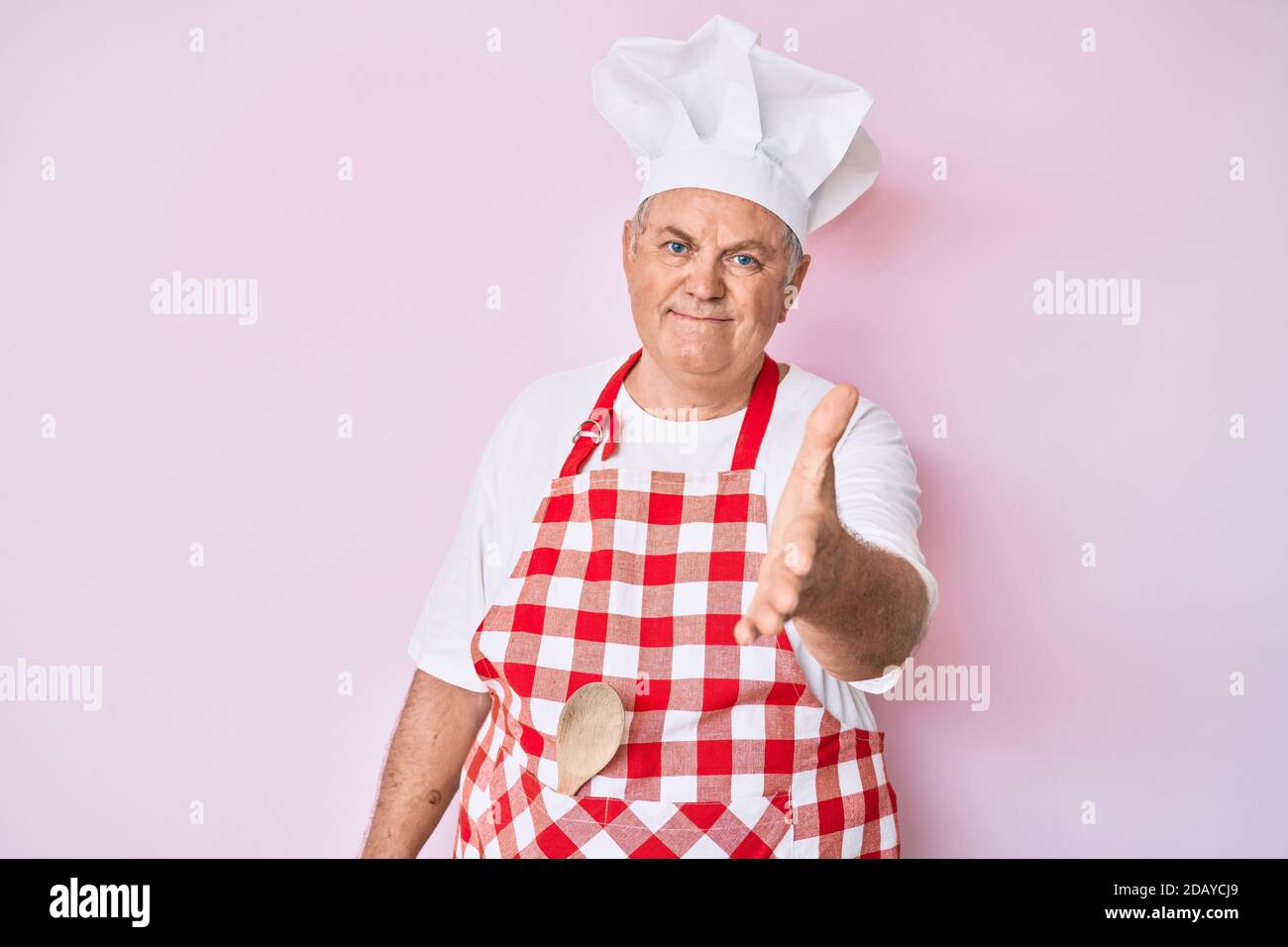 Senior grey-haired man wearing professional baker apron smiling ...