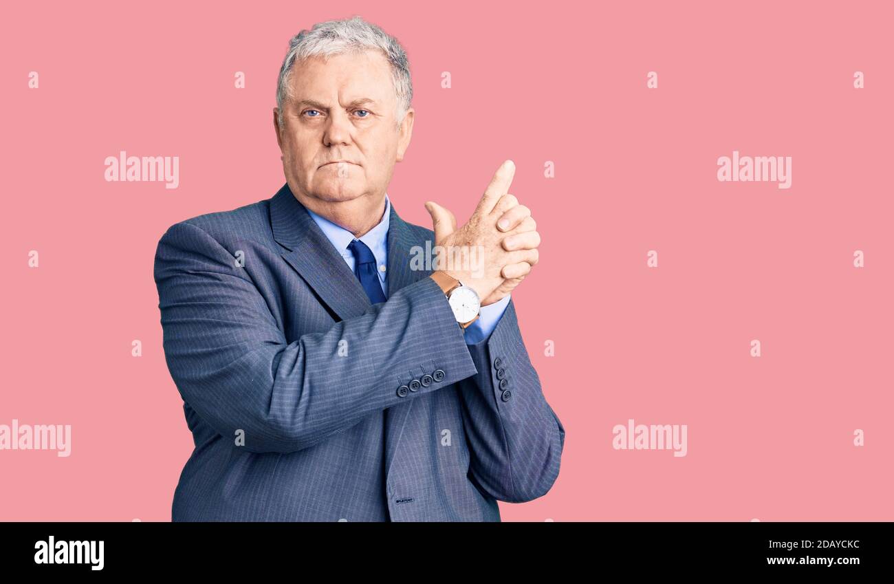 Senior grey-haired man wearing business jacket holding symbolic gun ...