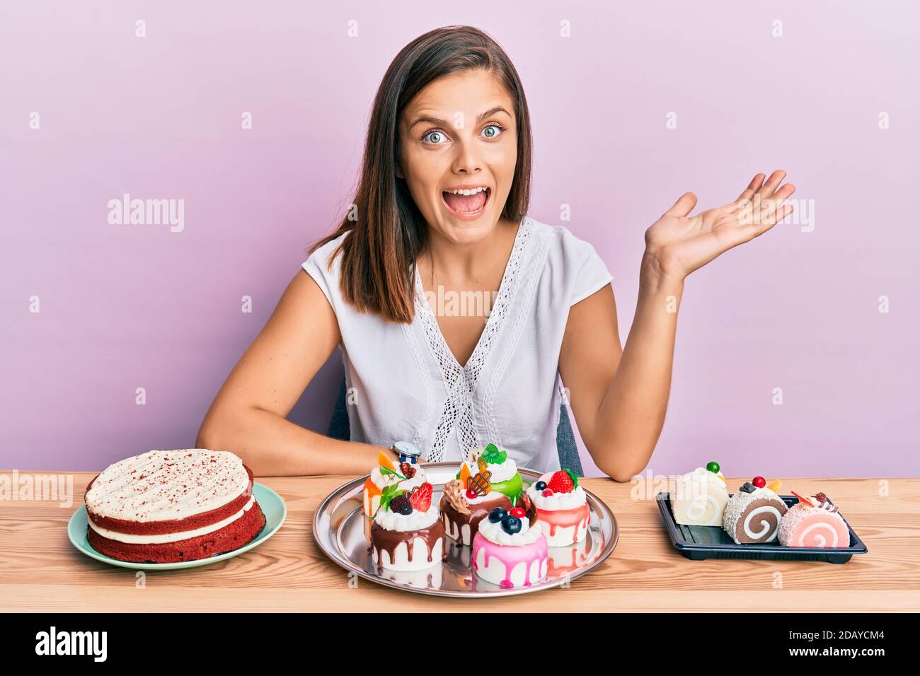 Young caucasian woman eating pastries celebrating victory with happy ...