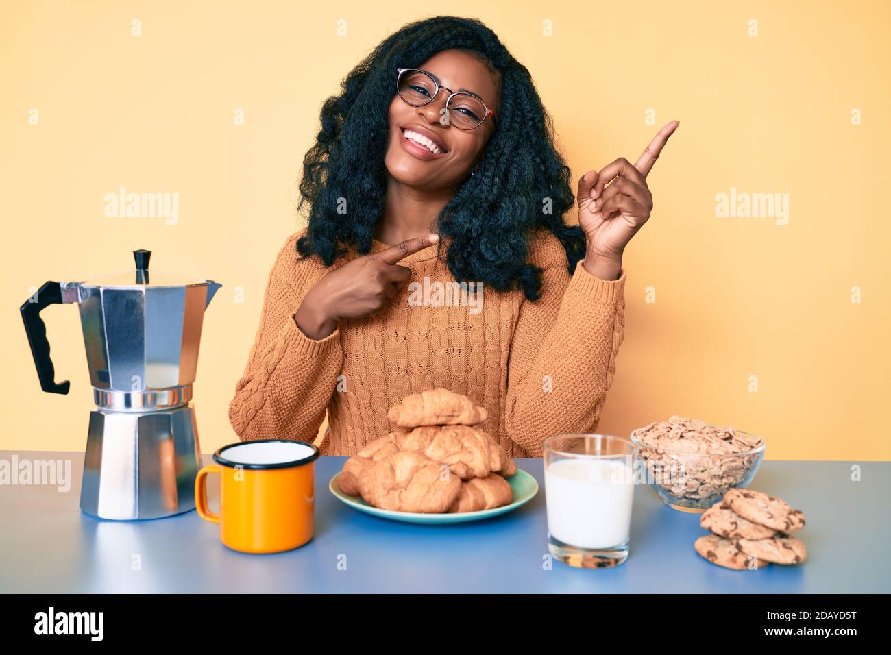 Beautiful african woman sitting on the table eating breakfast in the ...