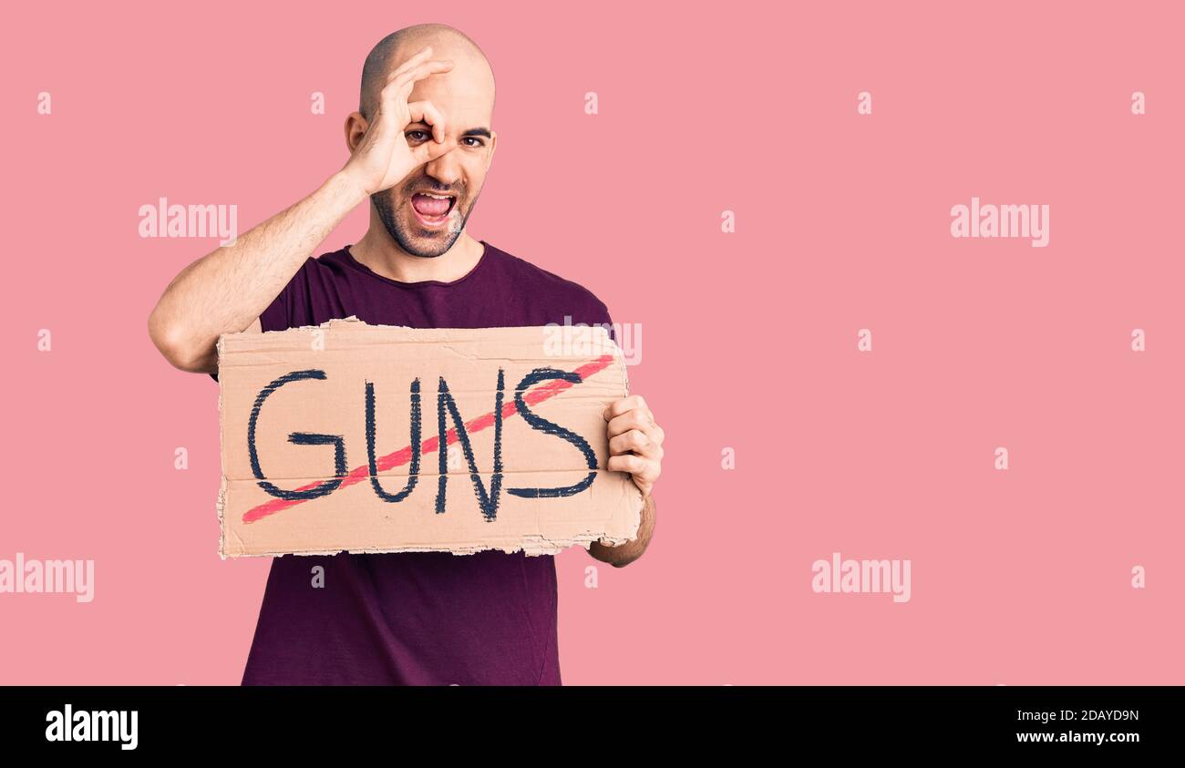 Young handsome man holding prohibited guns banner smiling happy doing ...