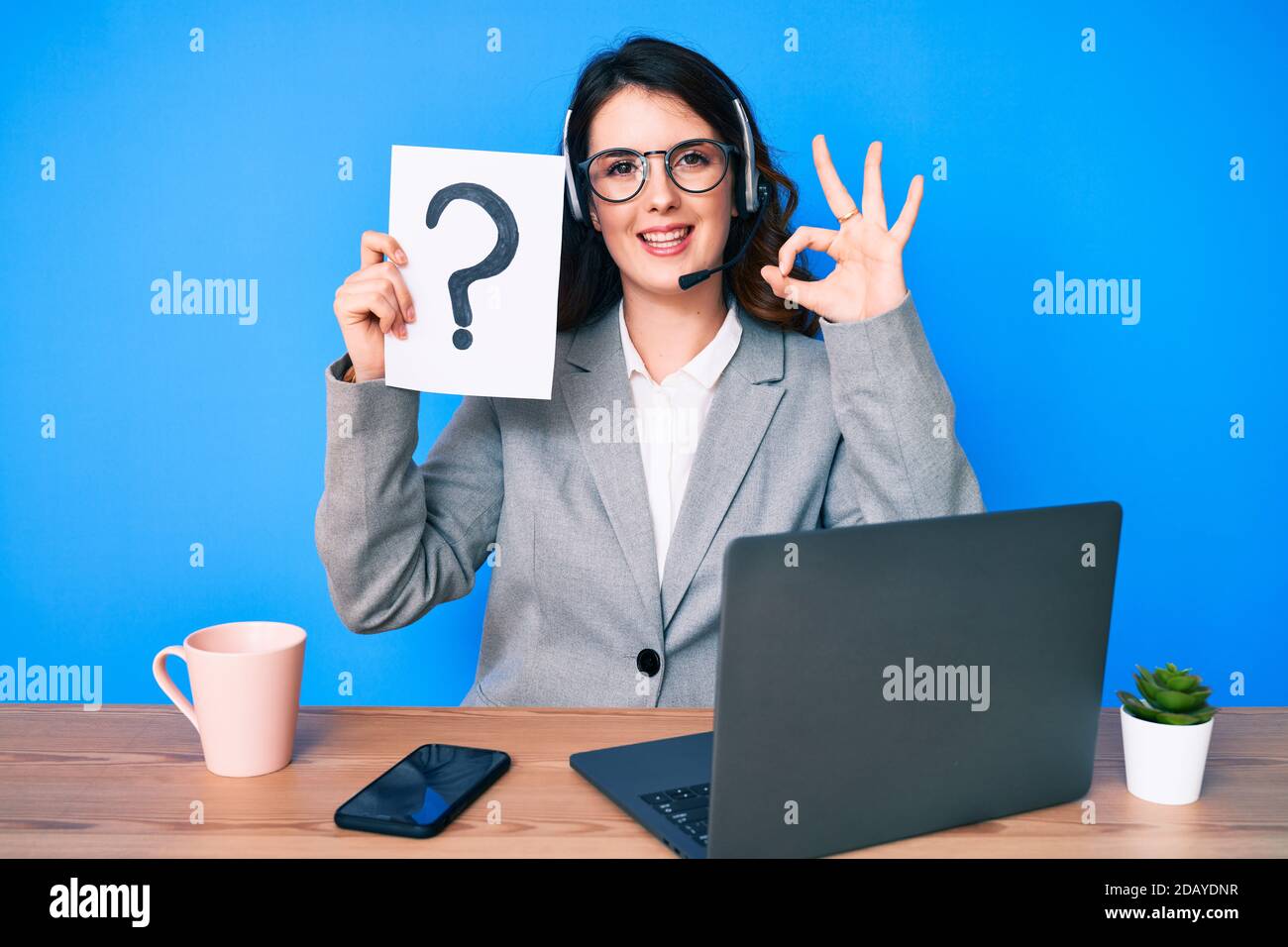 Young beautiful brunette woman wearing operator headset holding ...