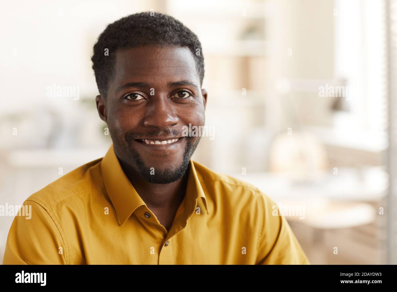 Head and shoulders portrait of smiling African-American man looking at camera while enjoying ...