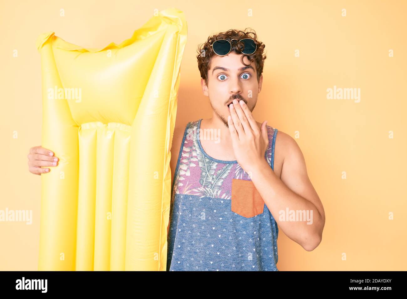 Young caucasian man with curly hair wearing summer clothes and holding ...