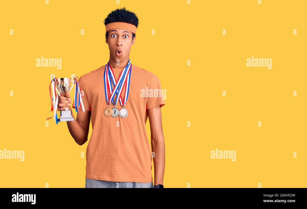 Young african american man holding champion trophy wearing medals ...
