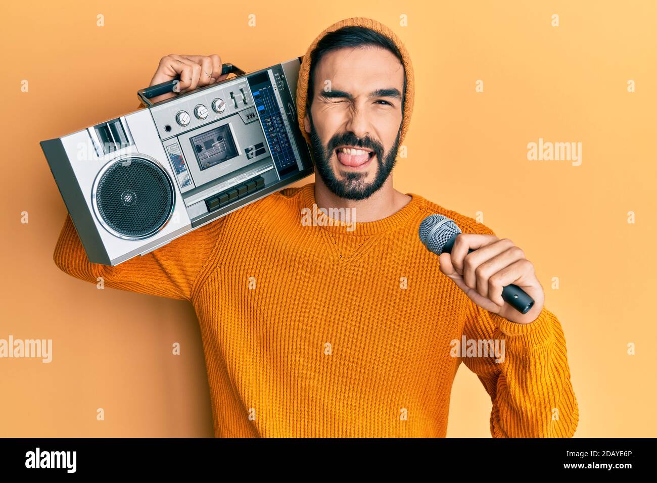 Young hispanic man with beard holding boombox listening to music ...
