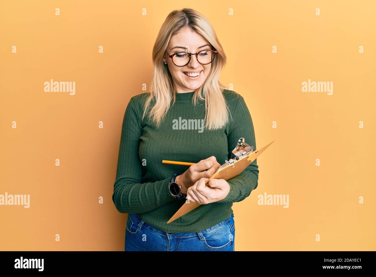 Young caucasian woman writing on checklist clipboard smiling with a ...