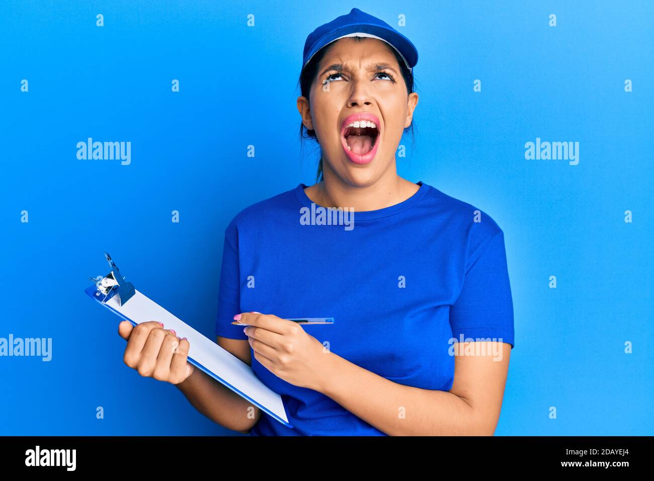 Beautiful brunette woman wearing courier uniform holding clipboard ...