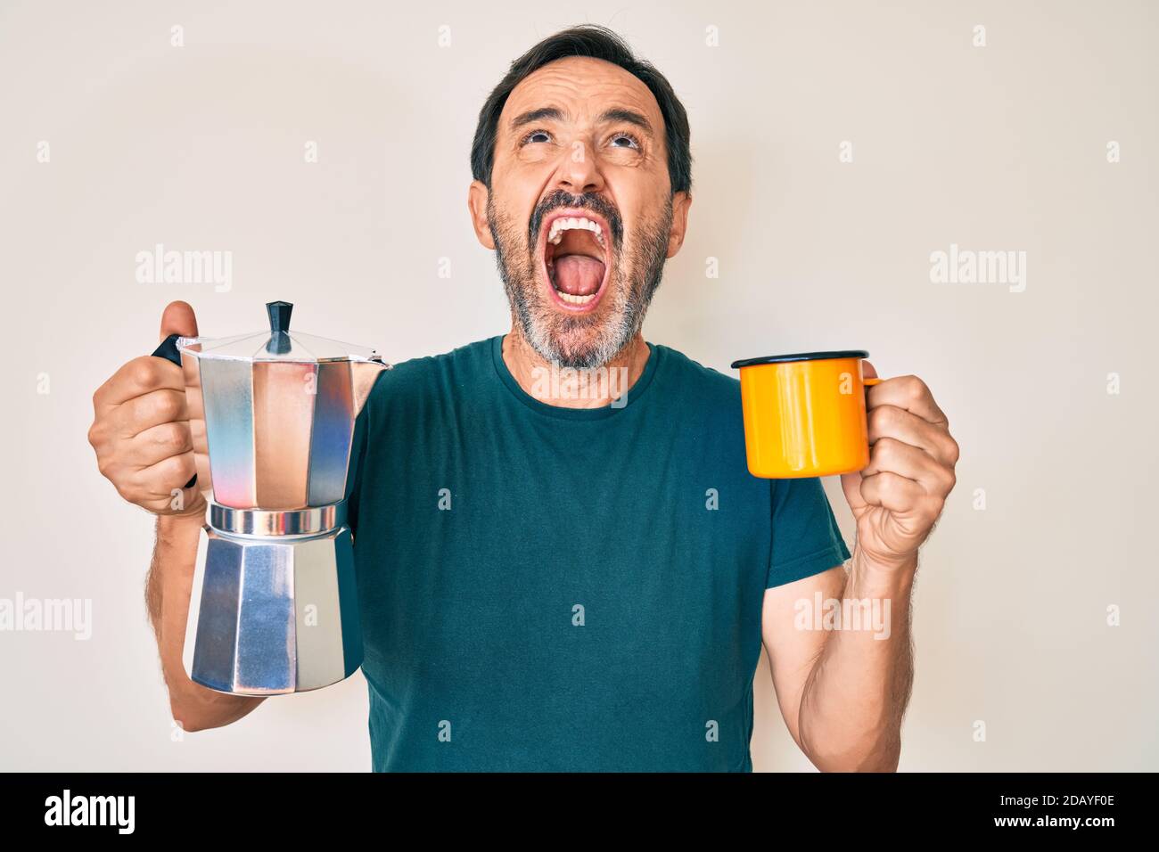 Middle age hispanic man holding italian coffee maker angry and mad ...