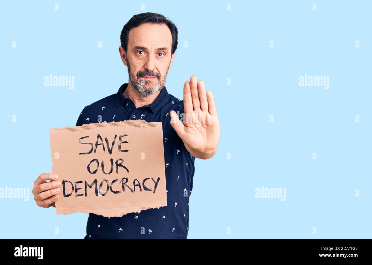 Middle age handsome man holding save our democracy cardboard banner ...