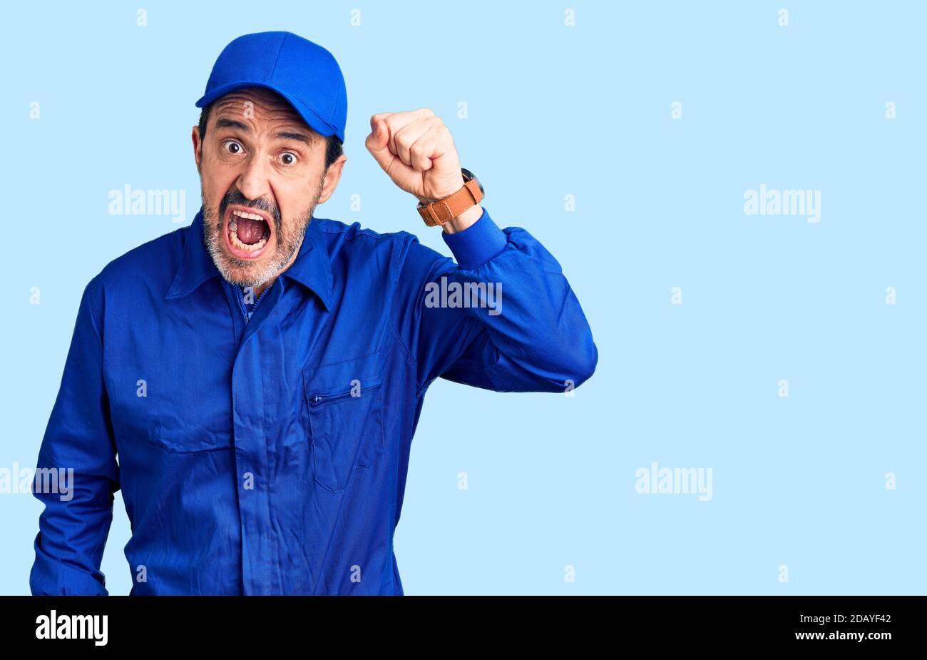 Middle age handsome man wearing mechanic uniform angry and mad raising ...