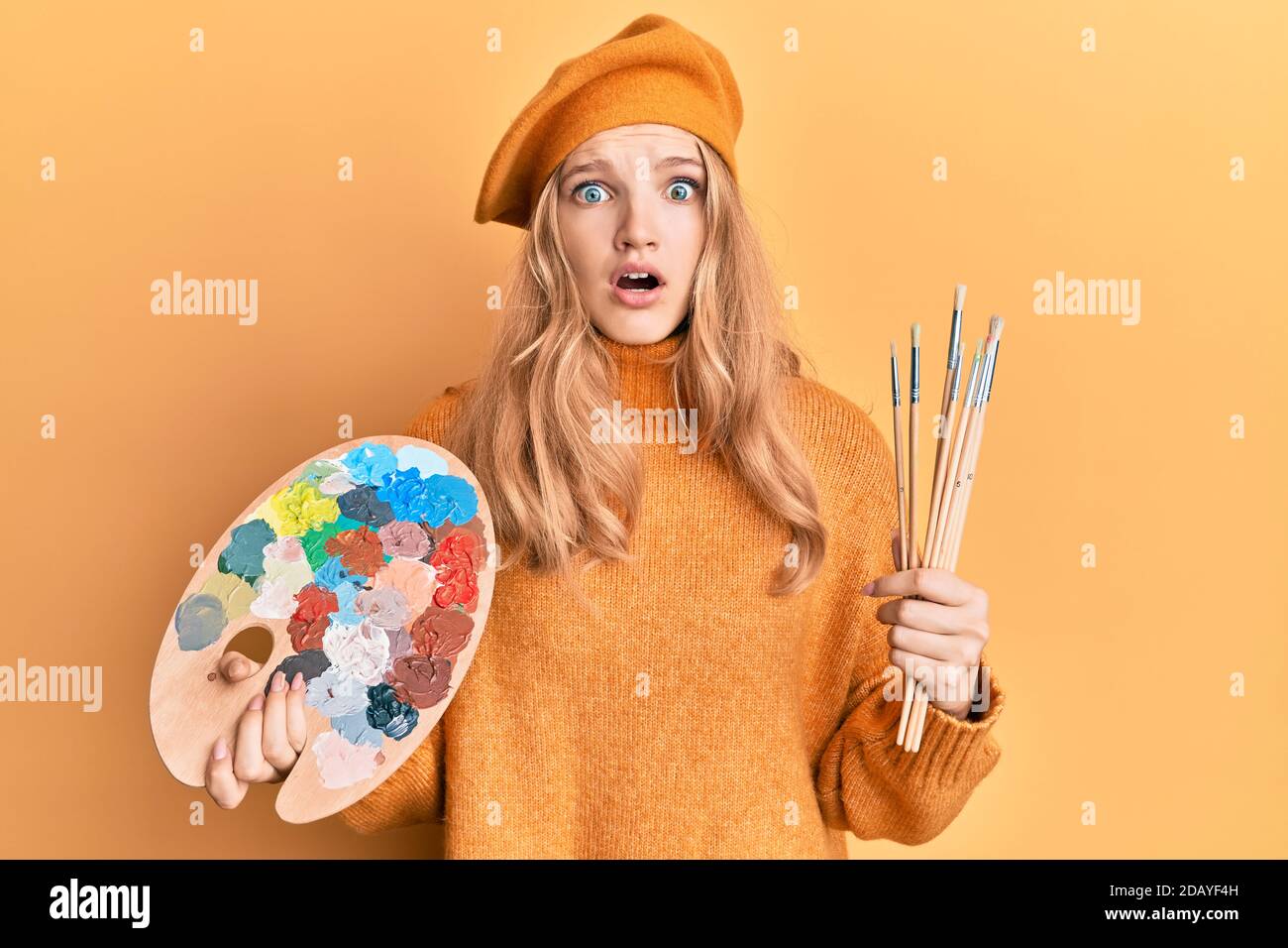 Beautiful young caucasian girl holding paintbrush and painter palette ...