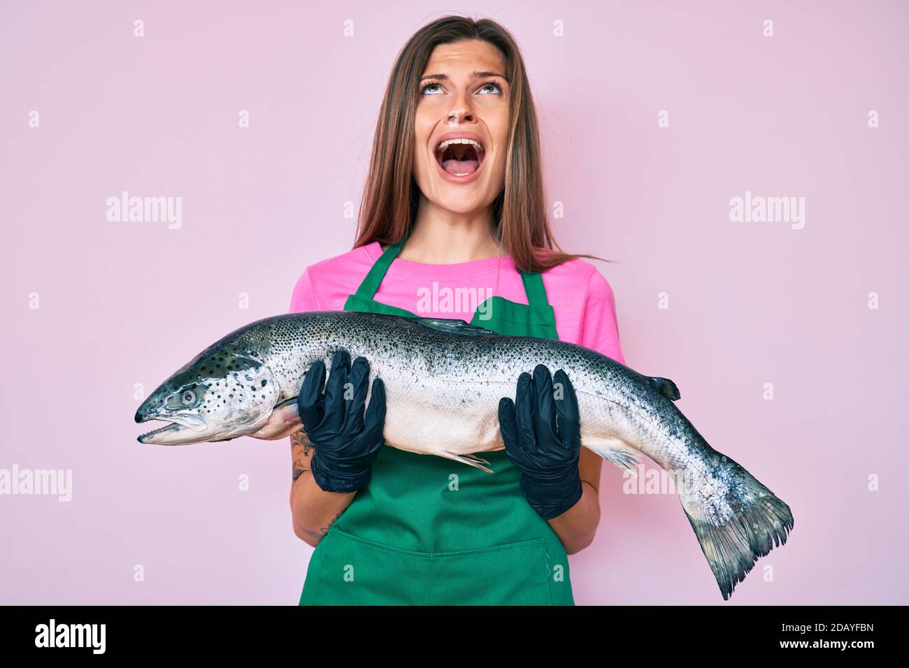 Beautiful caucasian woman fishmonger selling fresh raw salmon angry and ...