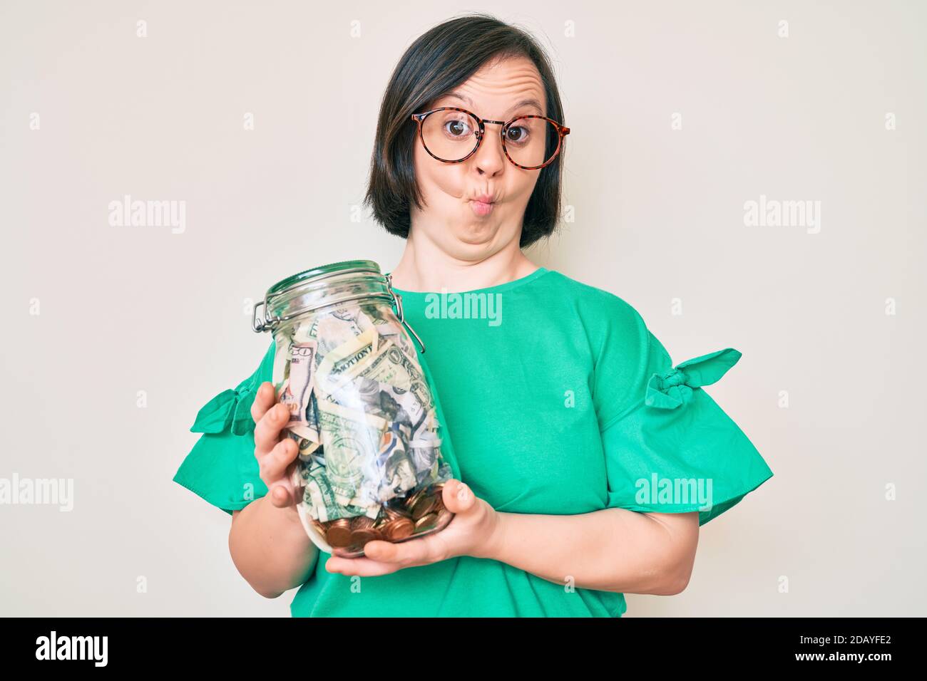 Brunette woman with down syndrome holding jar with savings making fish ...