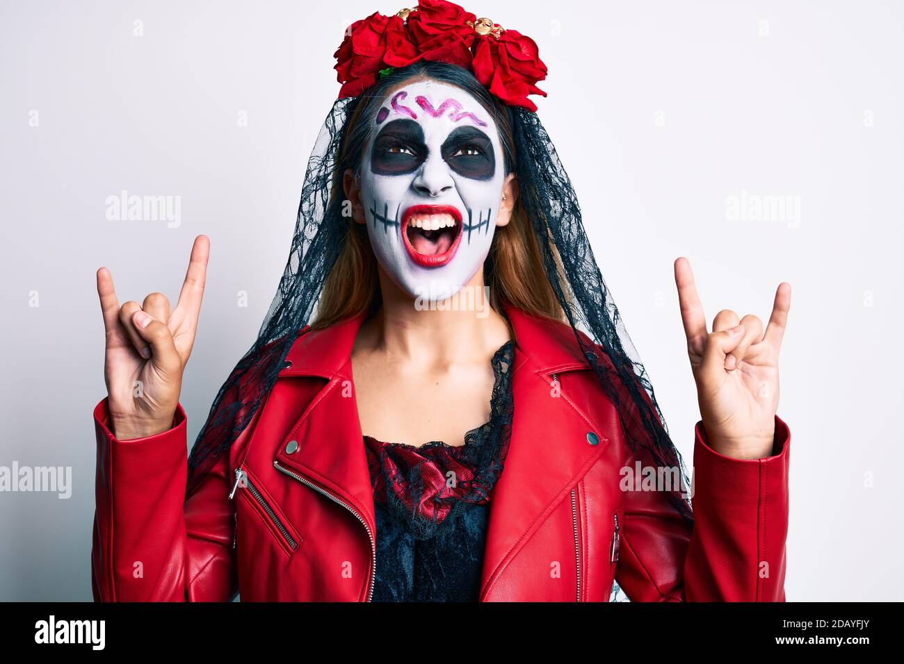 Woman wearing day of the dead costume doing rock and roll gesture with ...