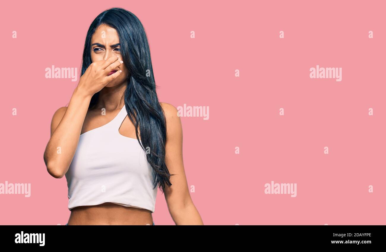 Beautiful Hispanic Woman Wearing Casual Clothes Smelling Something Stinky And Disgusting