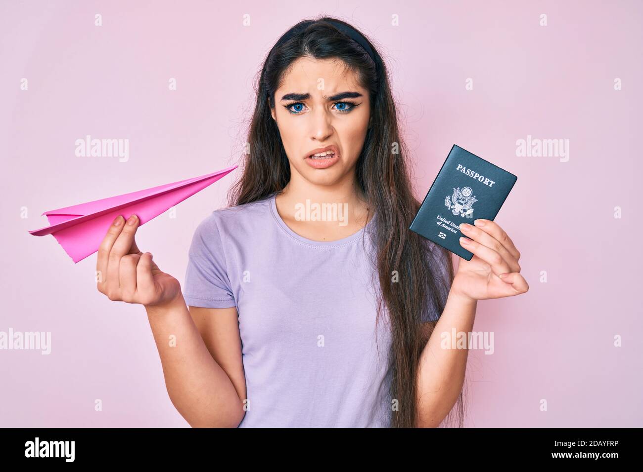 Brunette teenager girl holding paper airplane and usa passport clueless ...