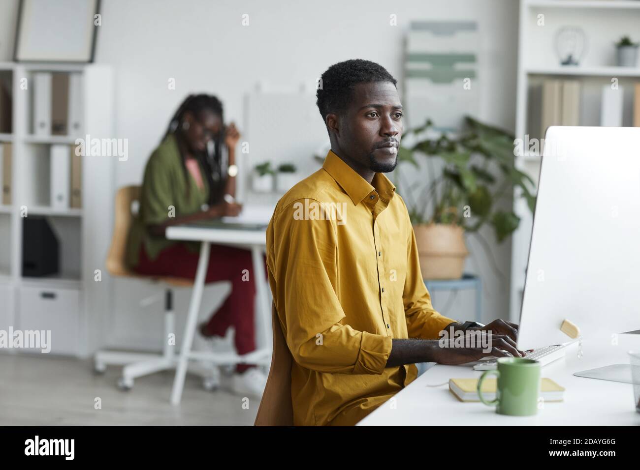 Side view at contemporary African-American man using computer while ...