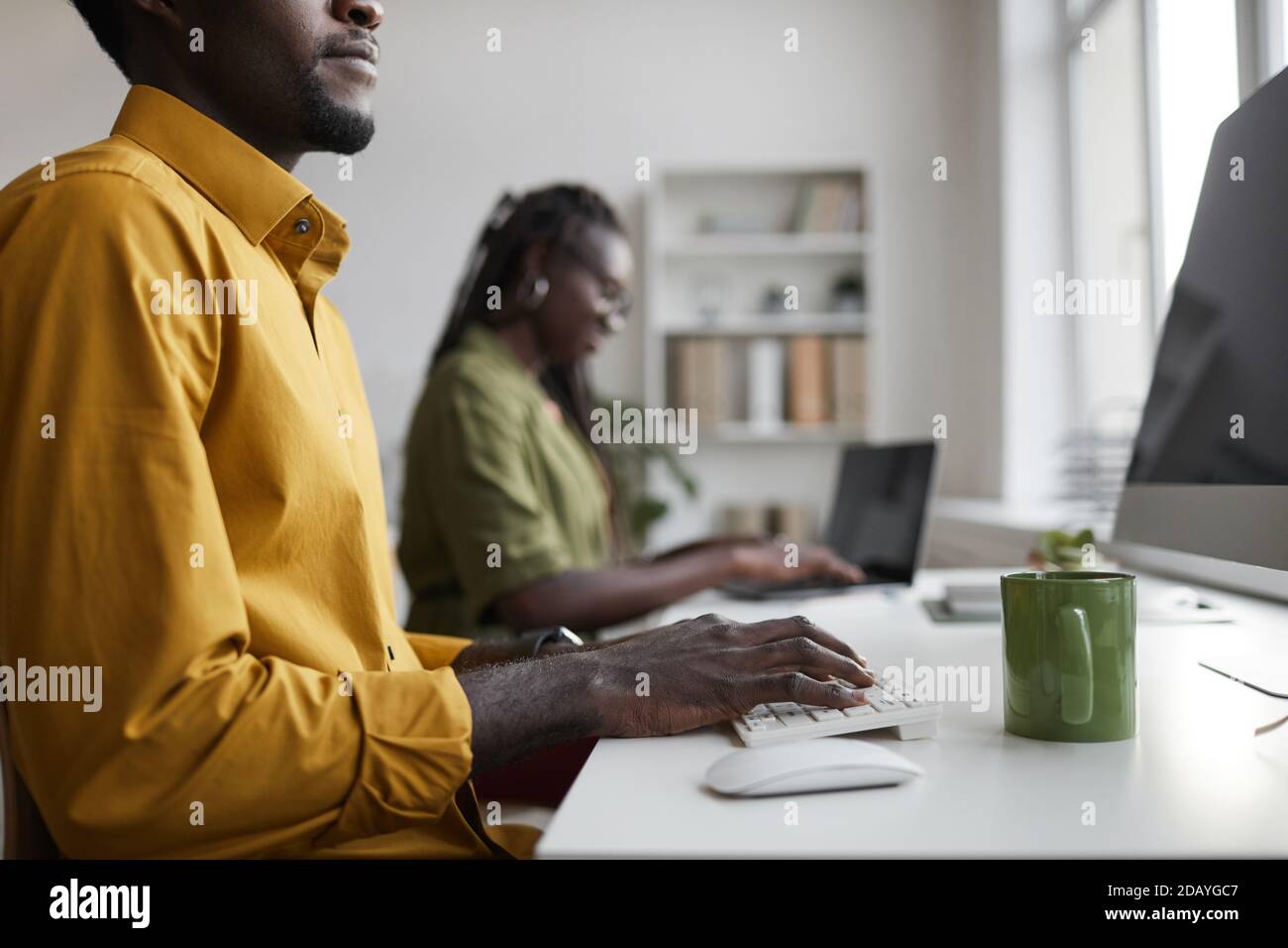 Cropped side view at young African-American man using PC in modern ...