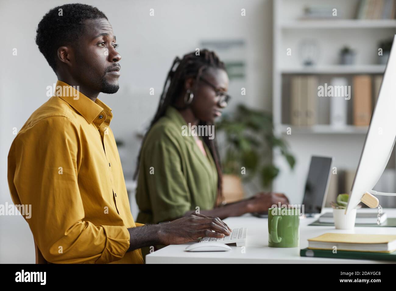 Side view portrait of young African-American man using PC in modern ...